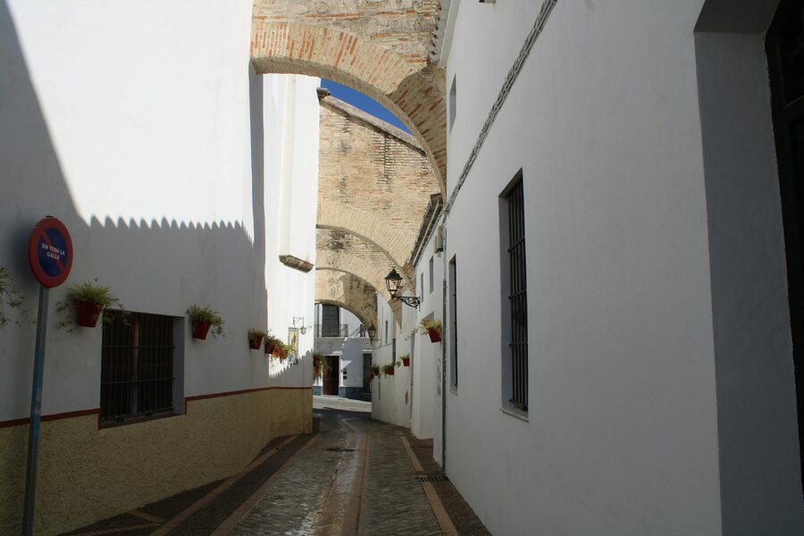 Narrow street with white buildings and historical arches in Granada Spain
