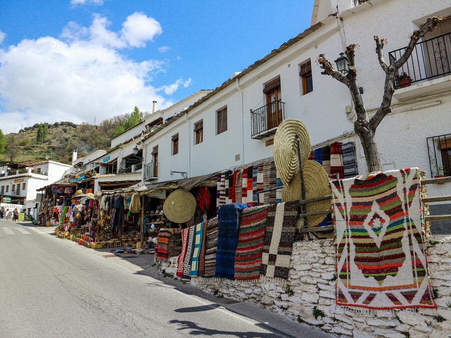 Colourful handmade rugs and souvenirs at an outdoor street market in Granada Spain