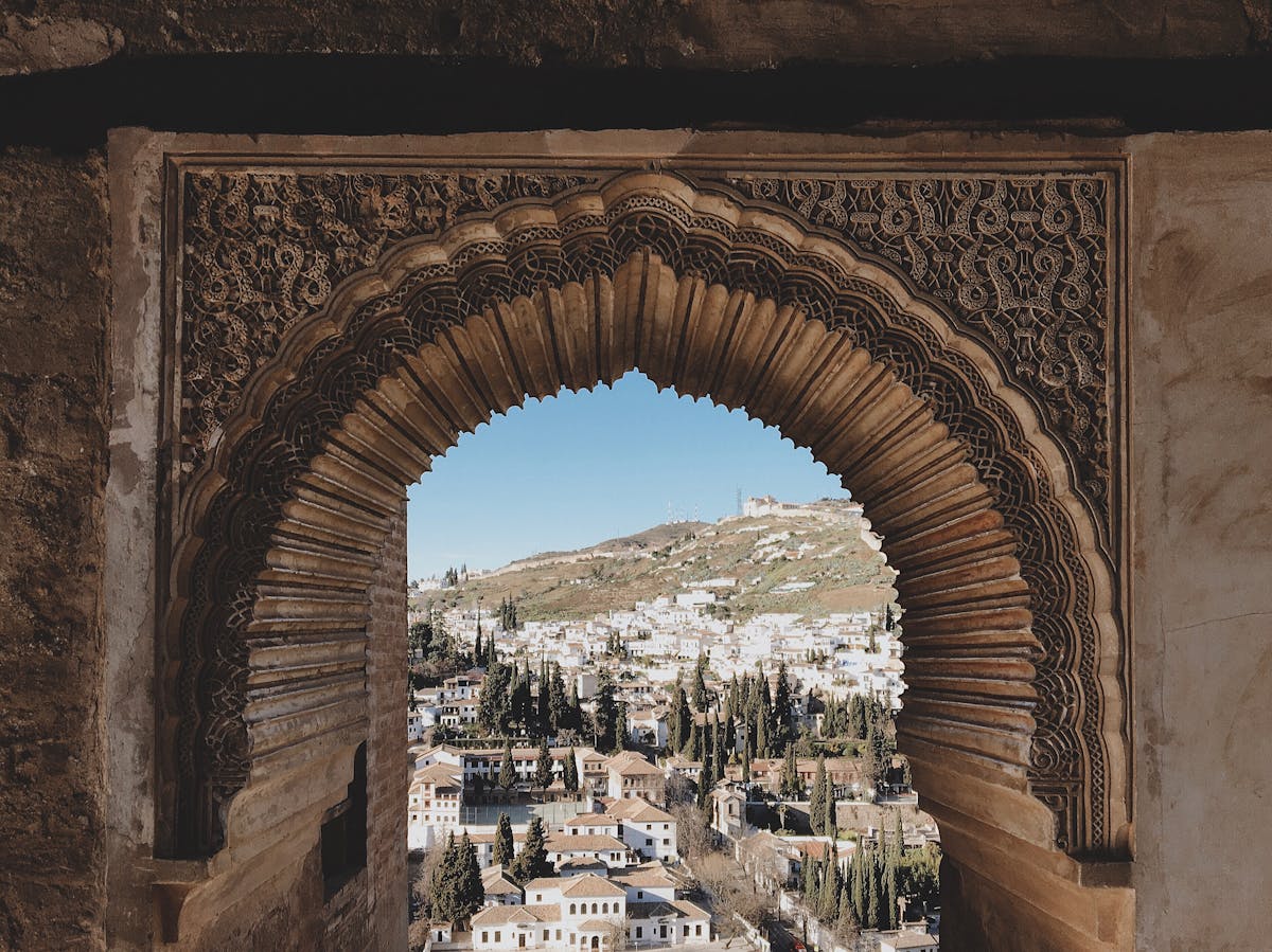 An ornately carved archway at the Alhambra frames a view of the city of Granada below