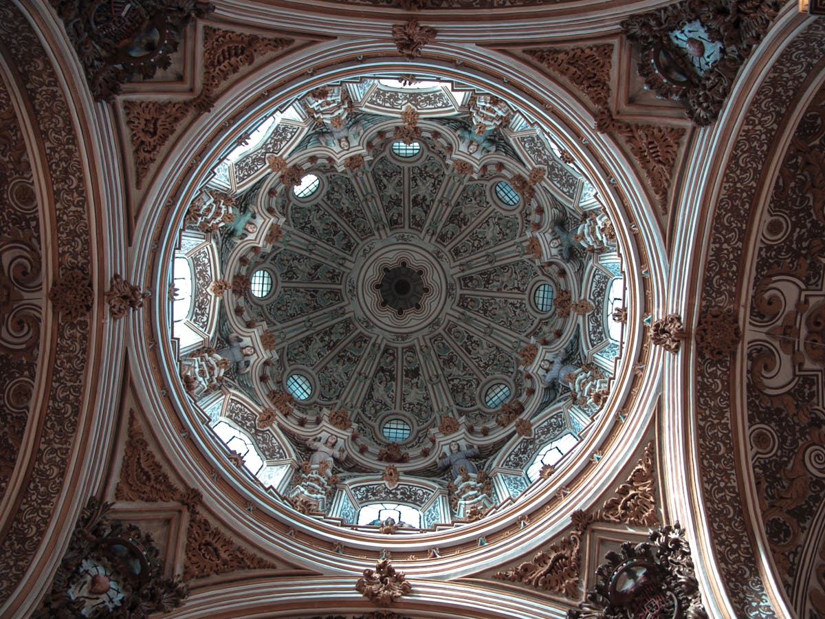 The painted dome ceiling inside Granada Cathedral showing religious frescoes and architectural details