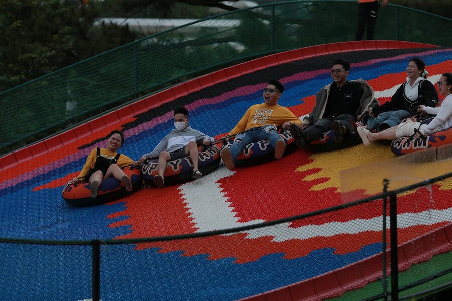 A group of adults having fun on an outdoor tubing ride, smiling and feeling exhilarated