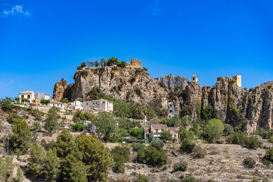 Dramatic rocky canyon with desert shrubs and clear blue sky near Guadalest village in Spain