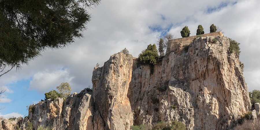 The ruins of Castell de Guadalest perched on top of a dramatic rocky cliff with mountain views in the background