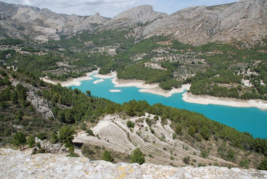 Stunning aerial shot of the turquoise Guadalest Reservoir surrounded by forested mountains
