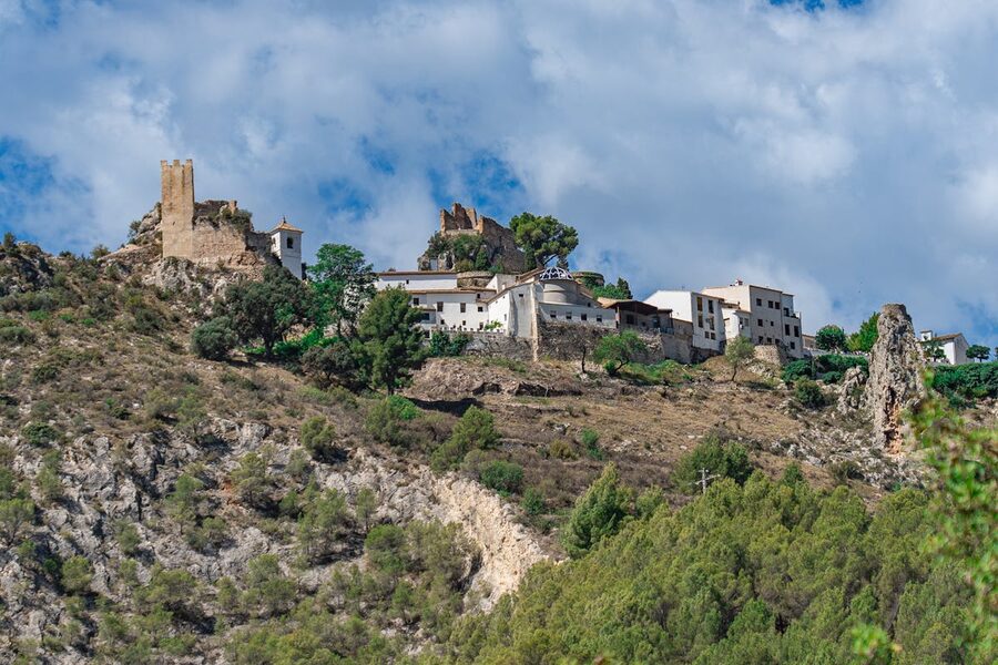 Scenic view of Guadalest hilltop village with historic stone buildings and lush green surroundings