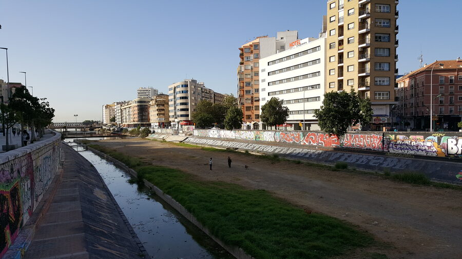 View of the Guadalmedina River flowing through Malaga with city buildings on both sides