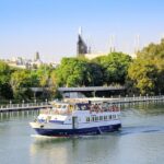 A sightseeing cruise boat on the Guadalquivir River passing historic Seville buildings