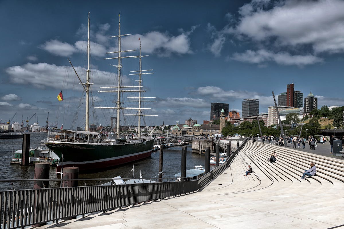 Tall ship in Hamburg harbor with the city skyline behind on a sunny day