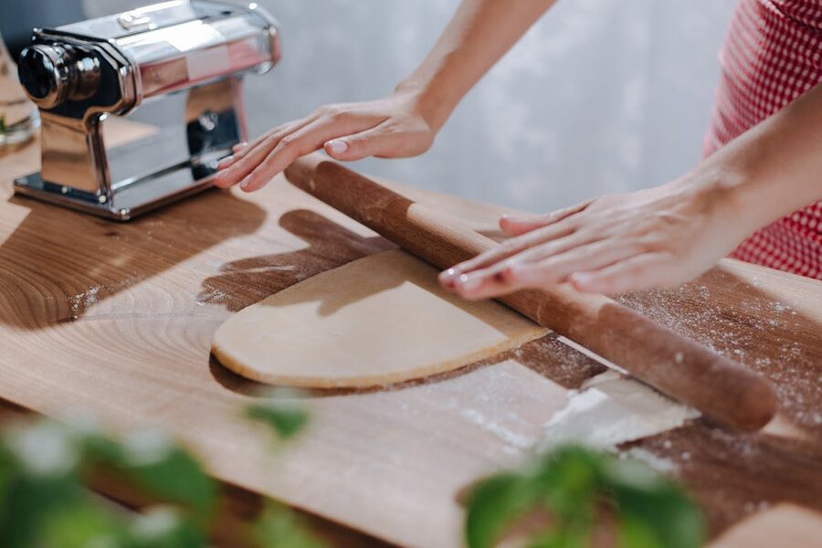 Close-up of hands rolling dough on a wooden board for fresh pasta making