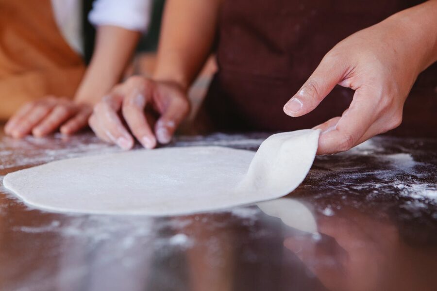 Close-up of hands shaping pizza dough on a floured surface highlighting artisan technique