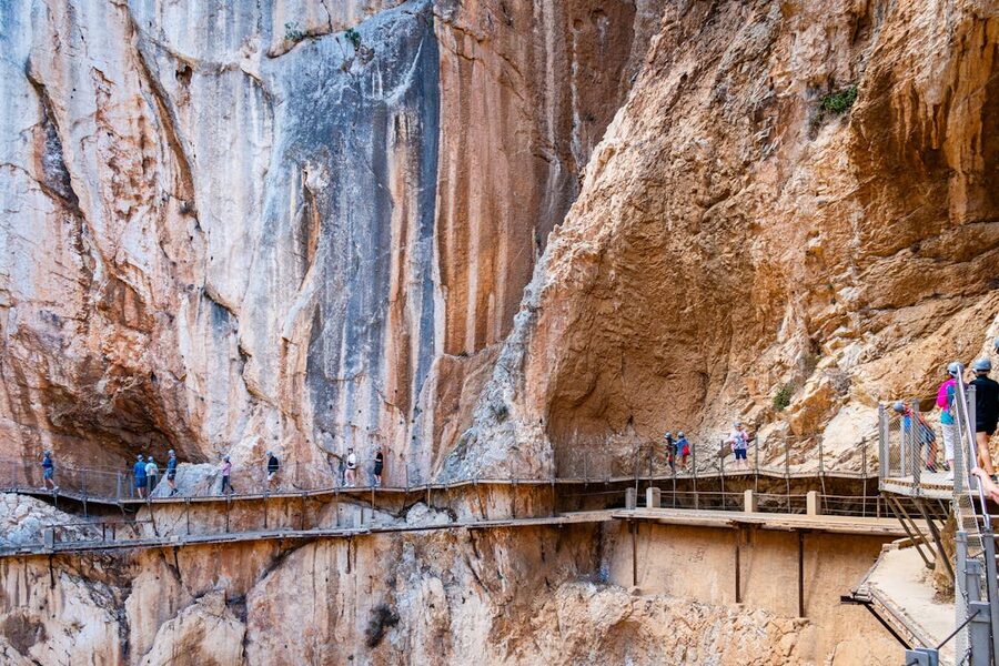 Hikers exploring the dramatic walkway of Caminito del Rey canyon trail in Spain