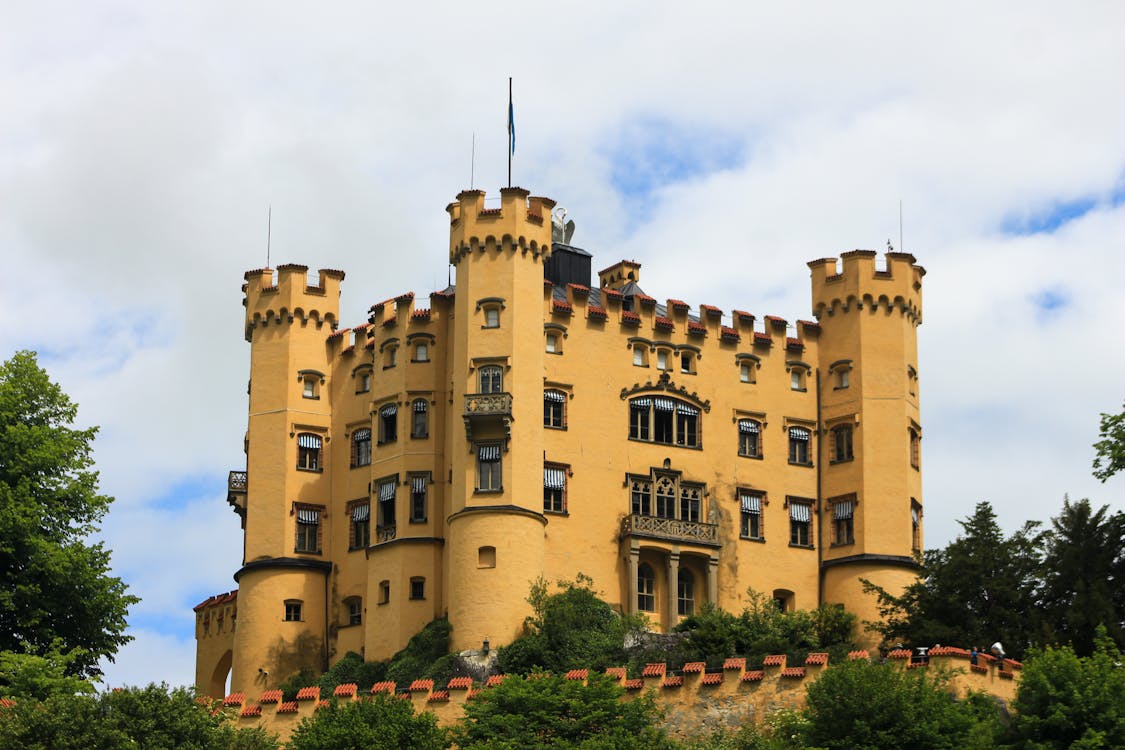 Yellow facade of Hohenschwangau Castle with Bavarian Alps in the background