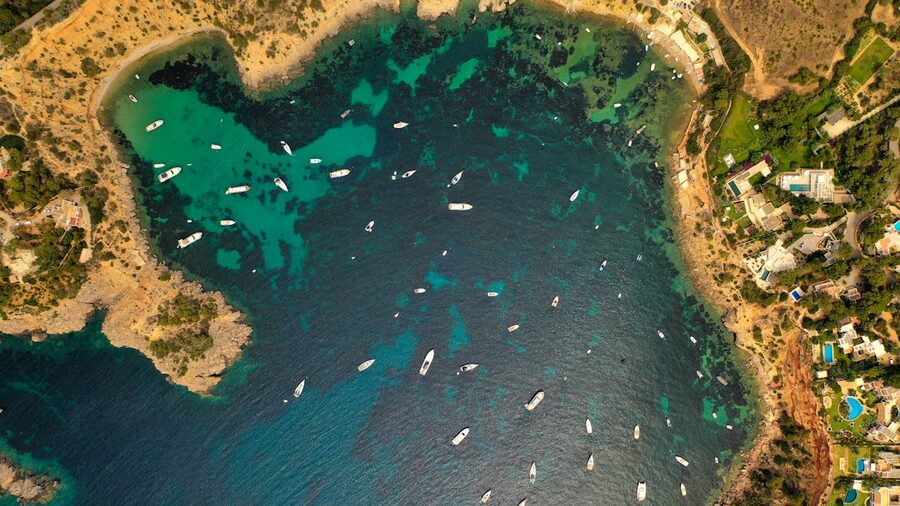 Aerial view of boats and clear turquoise waters along Ibiza coastline
