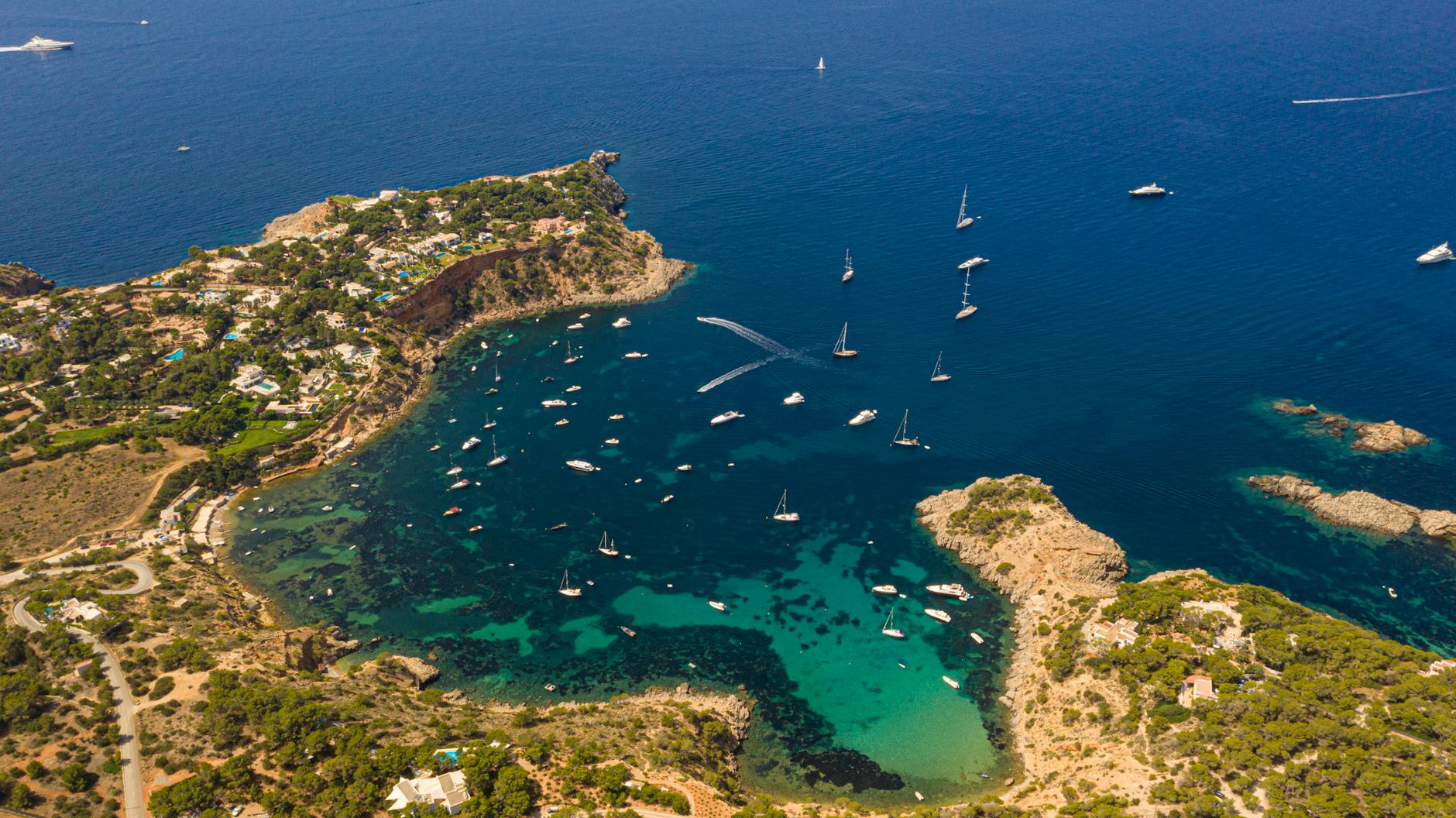 Aerial view of Ibiza's coastline with turquoise waters and boats