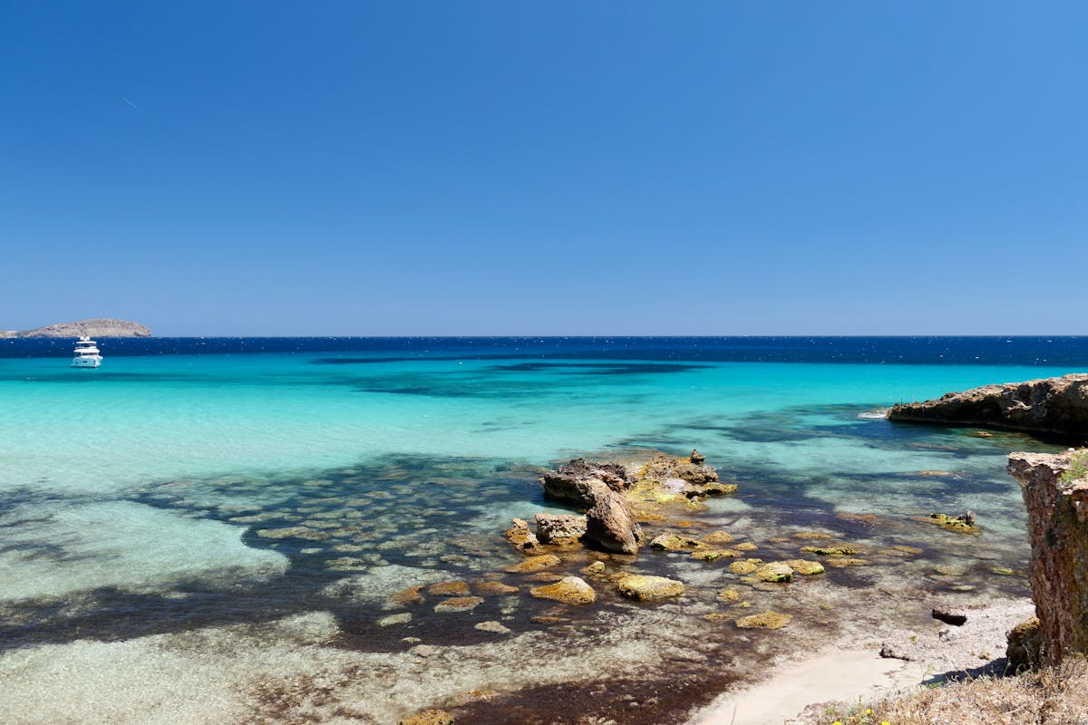 Rocky coastline of Ibiza with bright turquoise waters stretching to the horizon