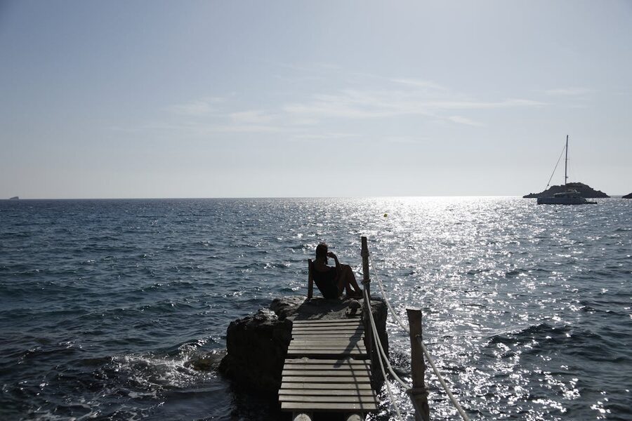 Silhouette on a wooden dock in Ibiza against a shimmering ocean sunset