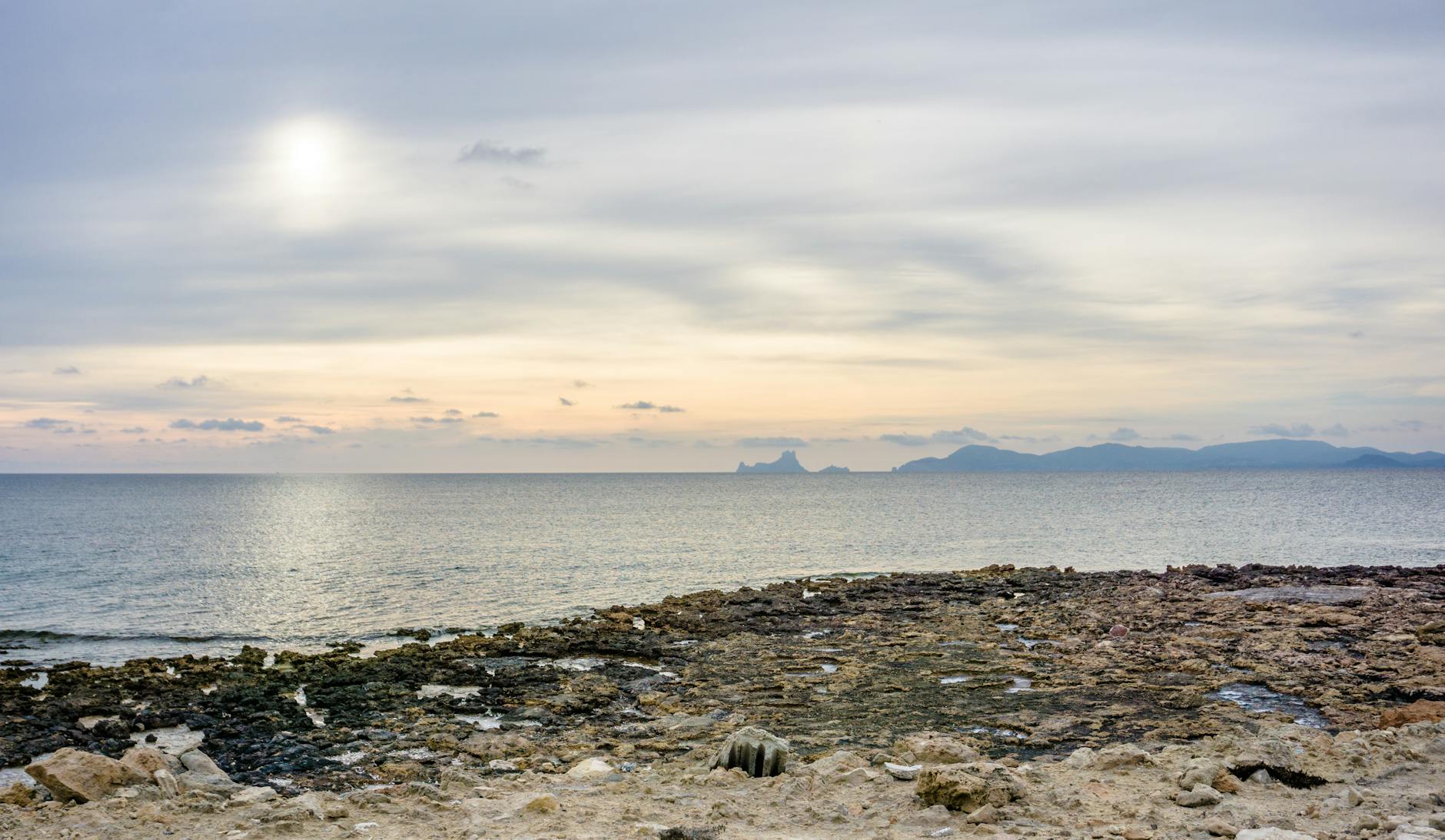 Rocky coastline of Ibiza at sunset with waves crashing