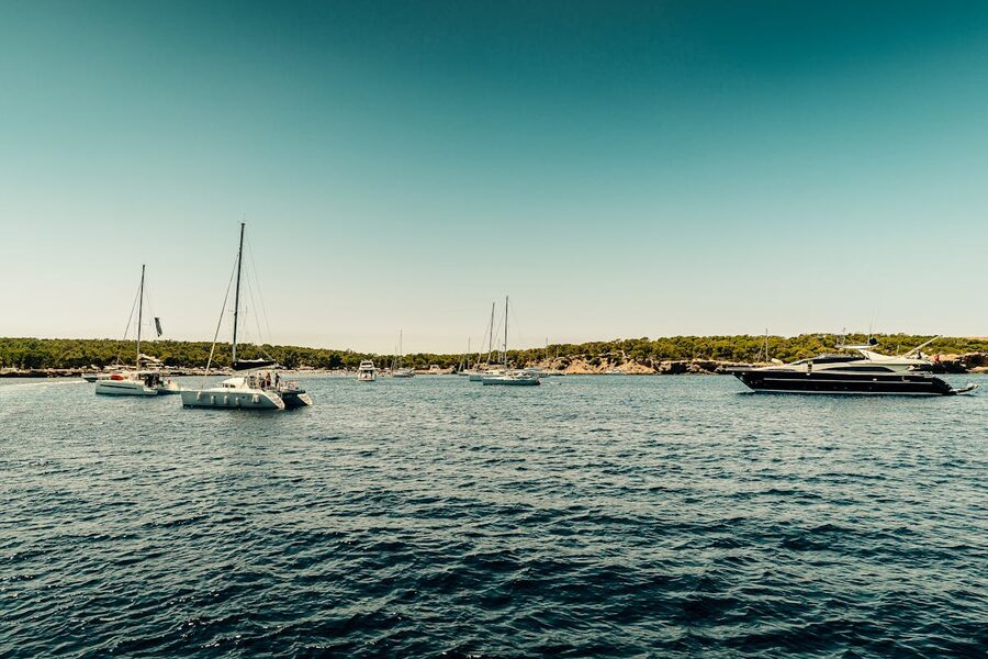 Picturesque scene of sailboats and yachts on Ibiza clear waters under bright sun