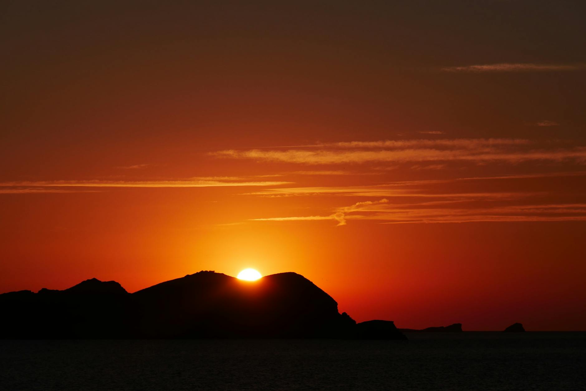 Orange sunset sky with silhouette of Ibiza coastline
