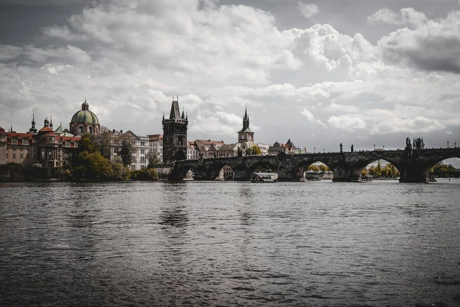 Sunset behind Charles Bridge casting golden light across the Vltava River in Prague