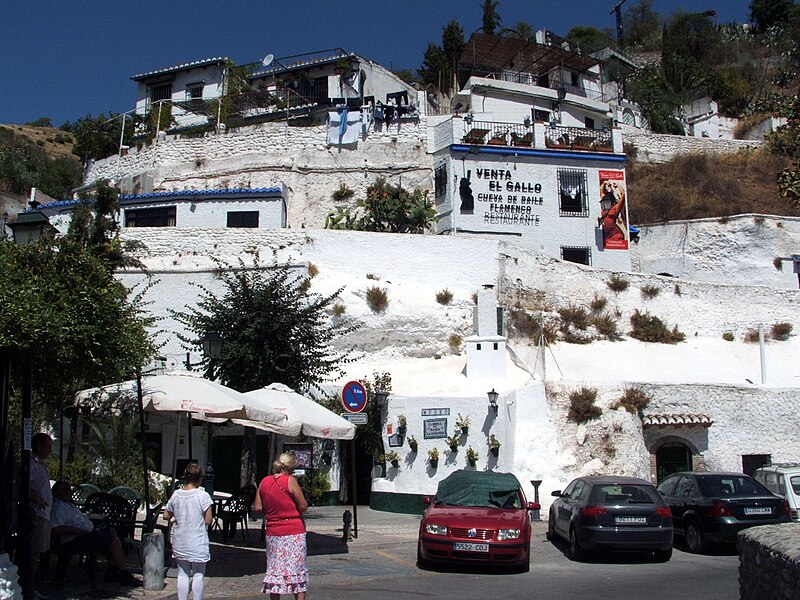 Green hillside of Sacromonte in Granada showing cave entrances and pathways