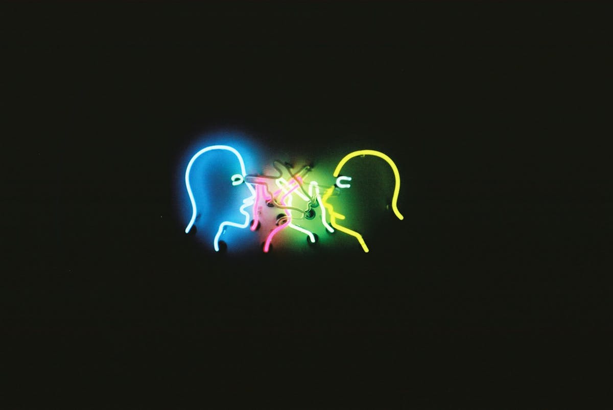 Colorful neon light art installation depicting faces on a dark background