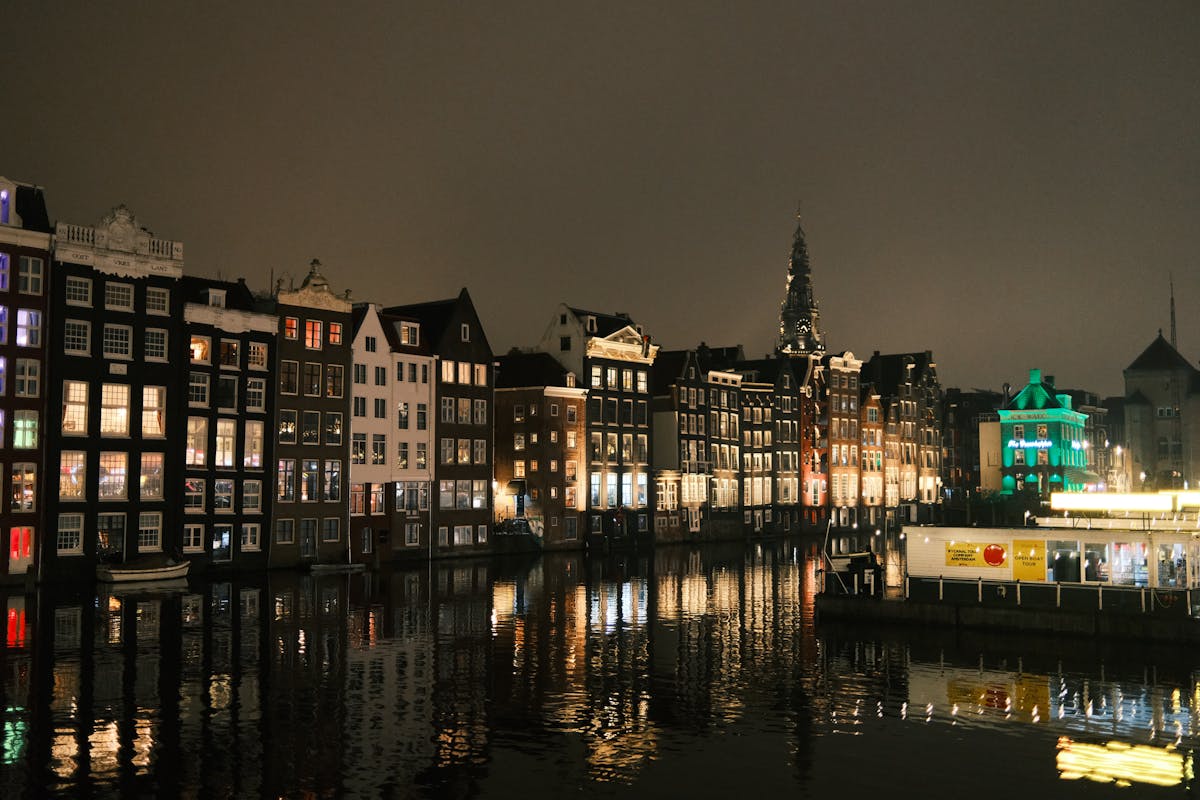 Scenic nighttime view of Amsterdam iconic canal houses reflecting on water