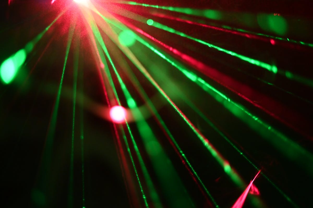 Dynamic display of red and green laser lights creating vivid rays across a dark space