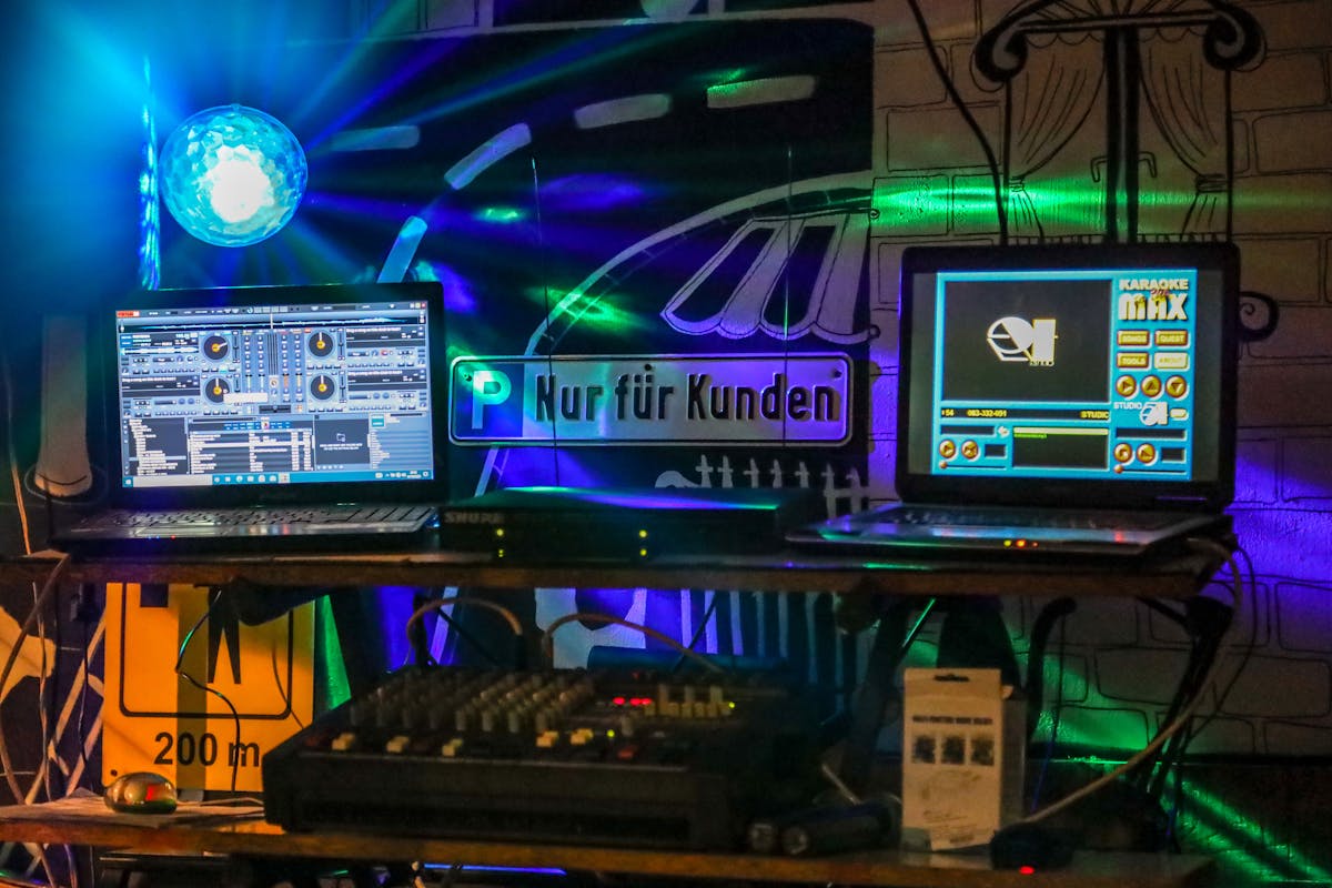 Vibrant DJ setup featuring laptops and a colorful disco light for nightlife