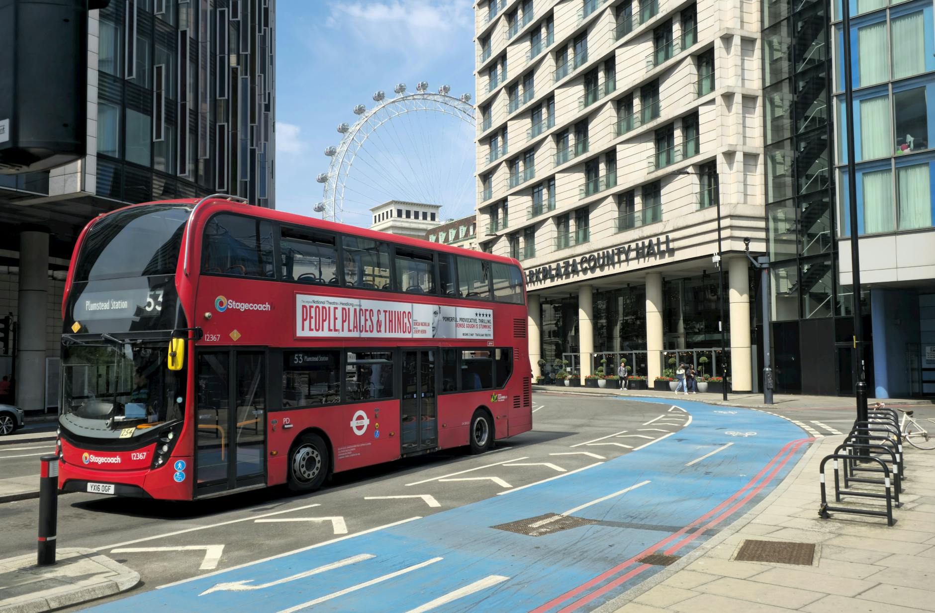 A classic red London bus with the London Eye visible behind it