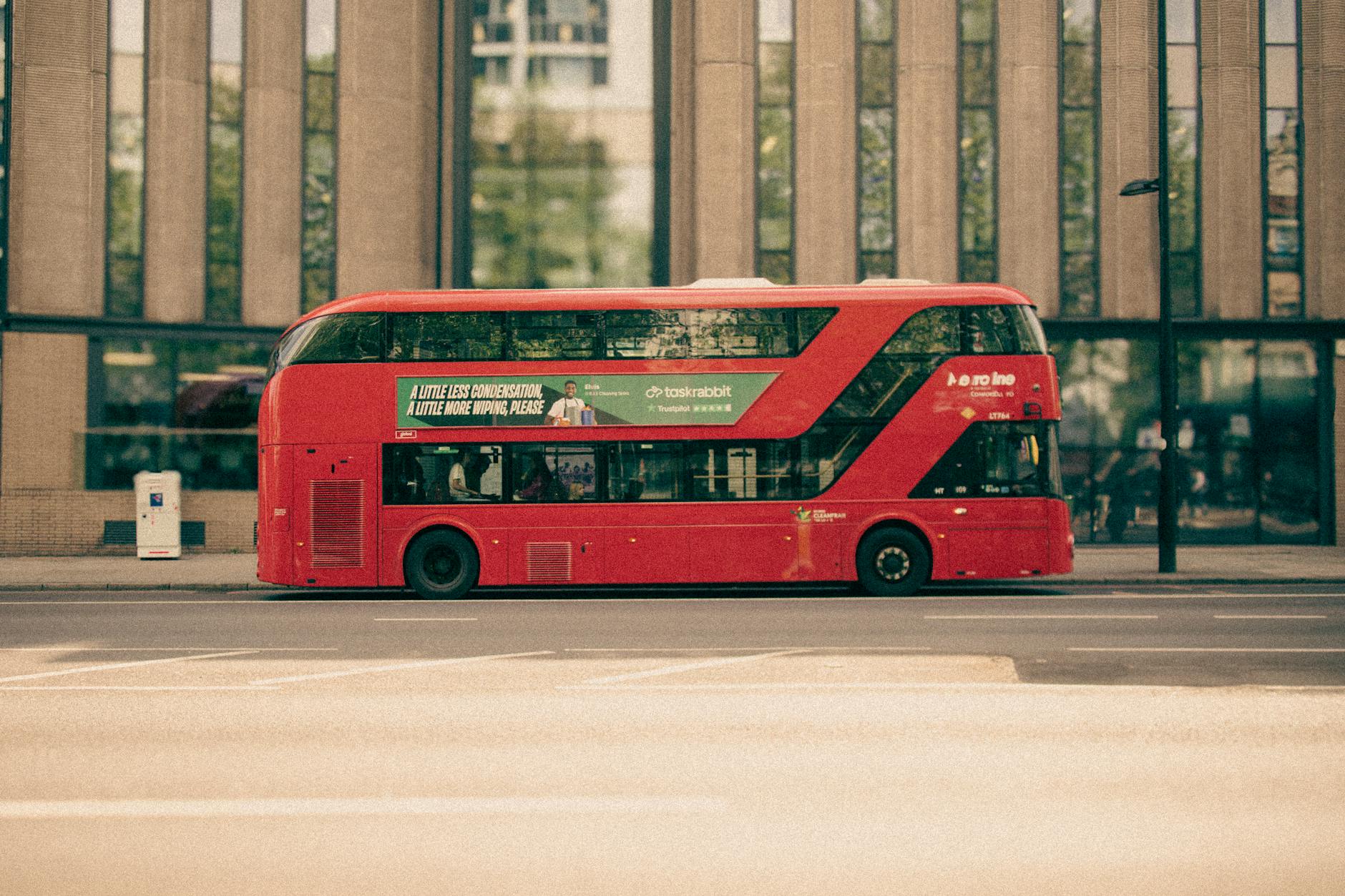 Red double-decker London bus driving through city streets