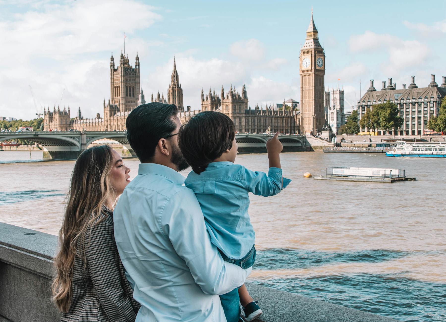 Family looking at Big Ben and Houses of Parliament from riverside
