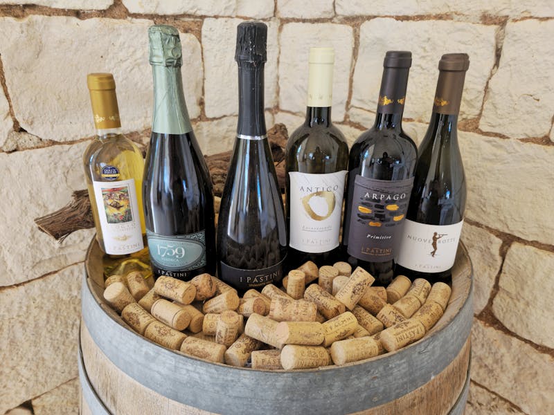 Five Italian wine bottles displayed on a rustic wooden barrel surrounded by wine corks