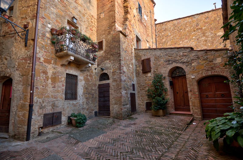 Charming stone alleyway with balconies and flower pots in the medieval streets of Pienza Tuscany