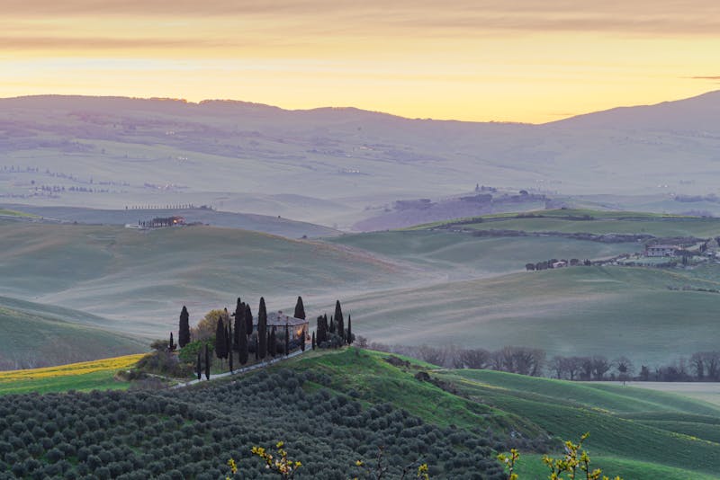 Golden sunrise over rolling hills and cypress trees in Val d Orcia Tuscany