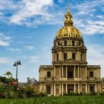 The golden dome of Les Invalides rising above Paris rooftops under a clear blue sky