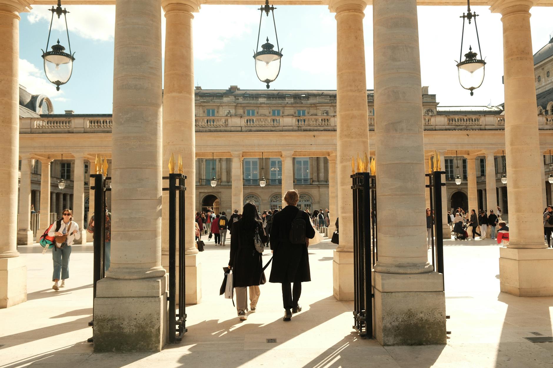 Classical Paris courtyard with columns and people walking through on a sunny day