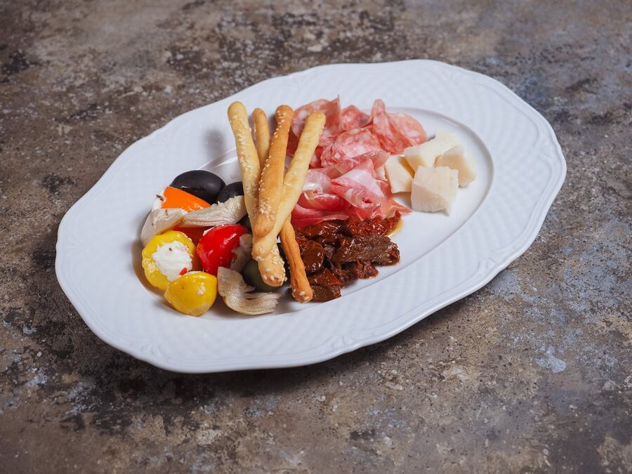 Italian antipasti platter with cured meats aged cheeses breadsticks and olive oil