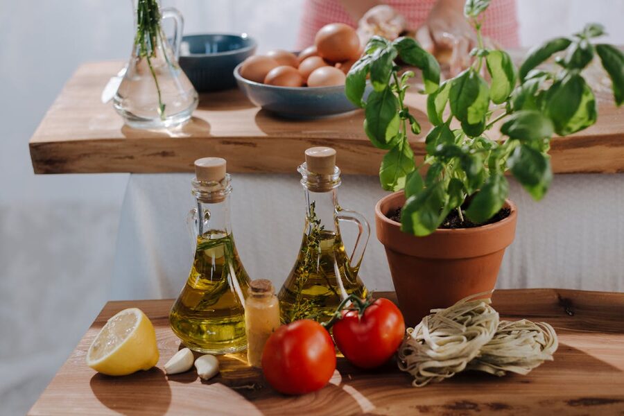 Fresh Italian cooking ingredients including olive oil, tomatoes, and basil on a wooden surface