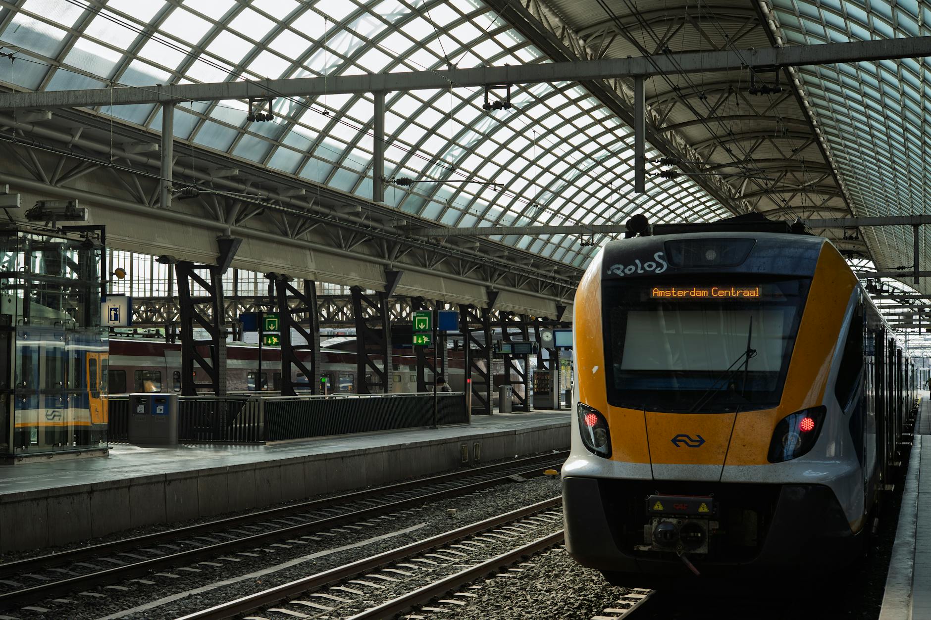 A modern train at Amsterdam Centraal Station under a glass roof