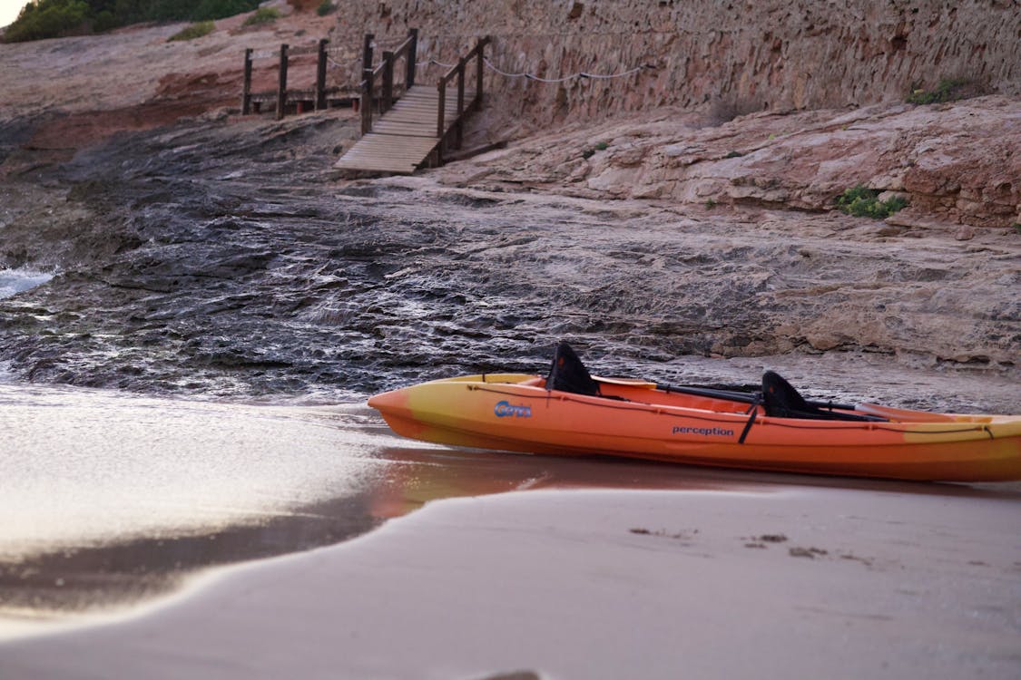 Bright kayak on a rocky shoreline ready for adventure