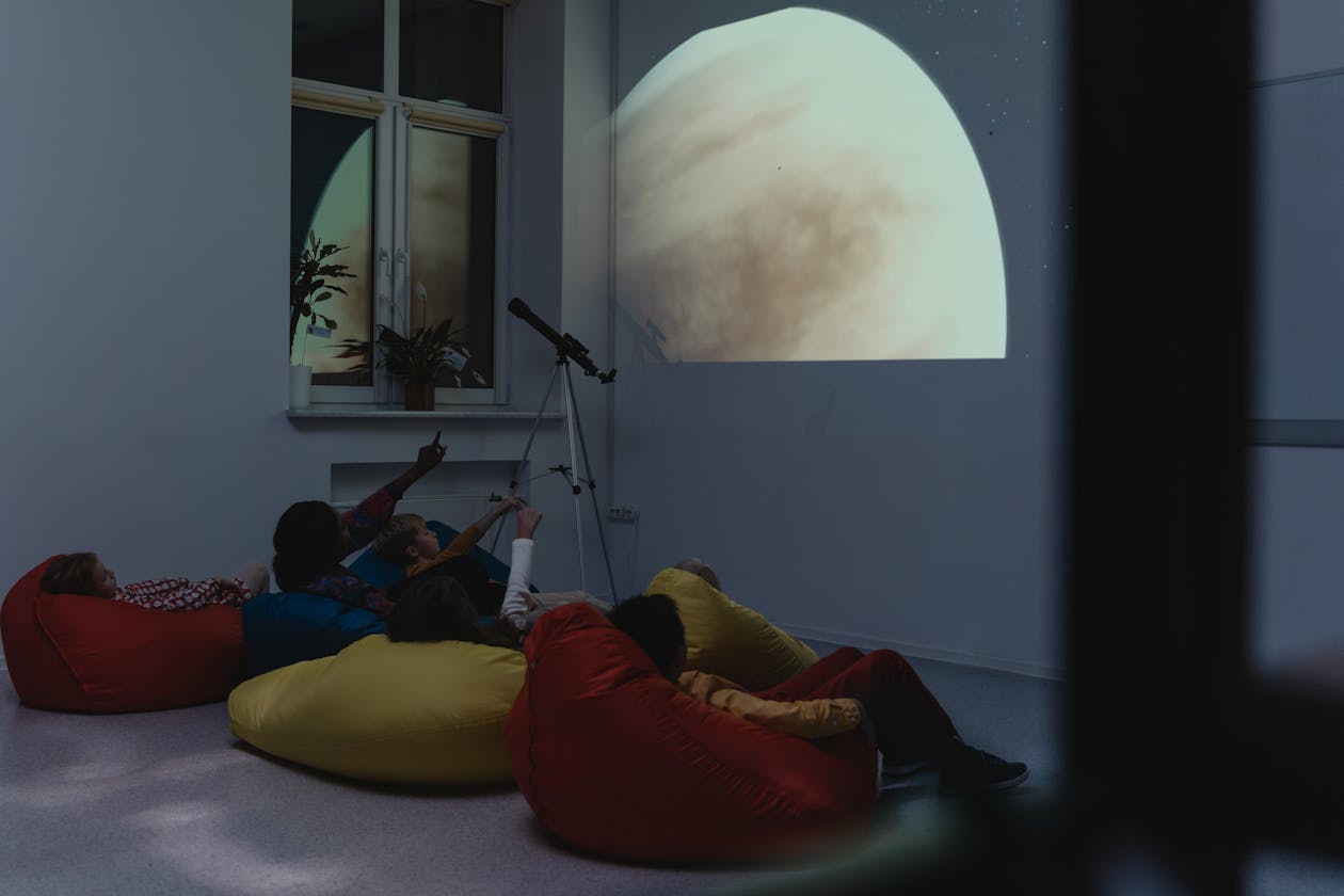 Group of children learning about astronomy with a telescope and projected planet images