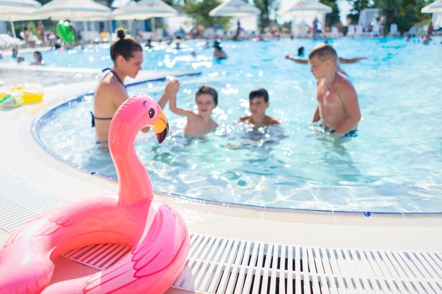 Children having fun playing in an outdoor swimming pool on a bright summer day