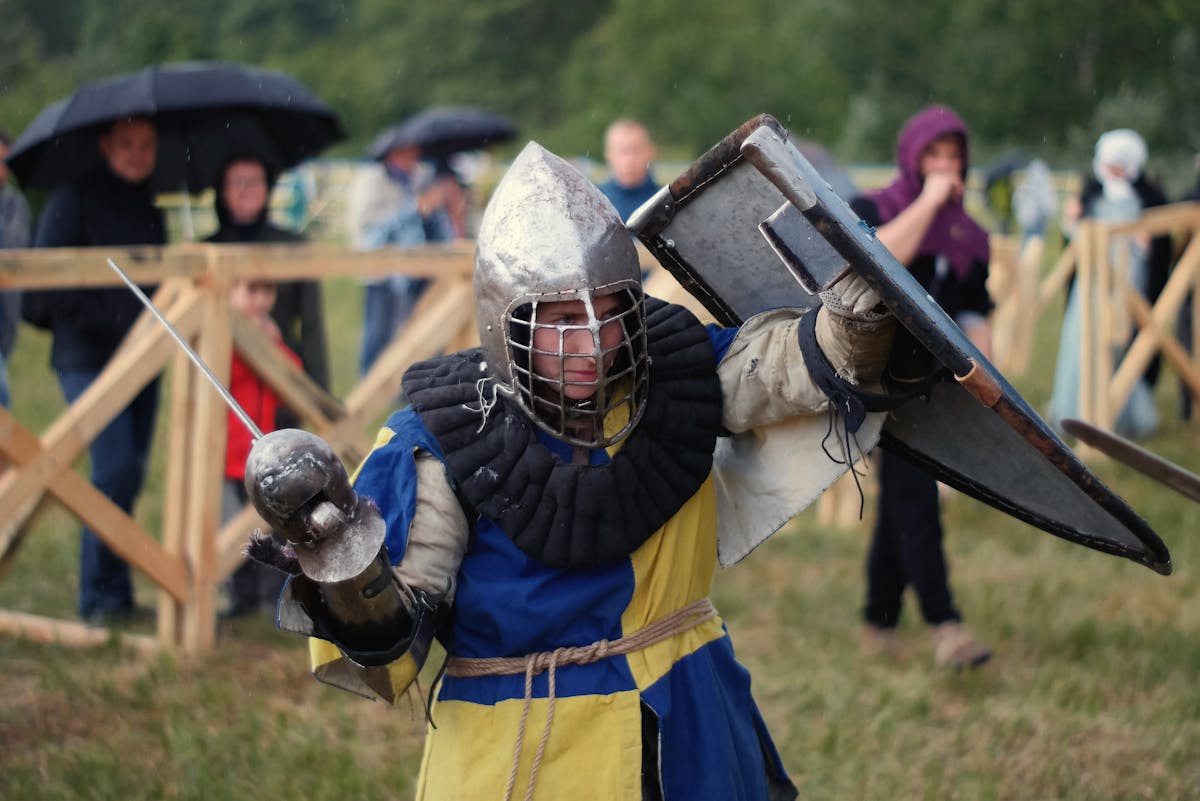 Knight in full armor with sword during a lively medieval reenactment