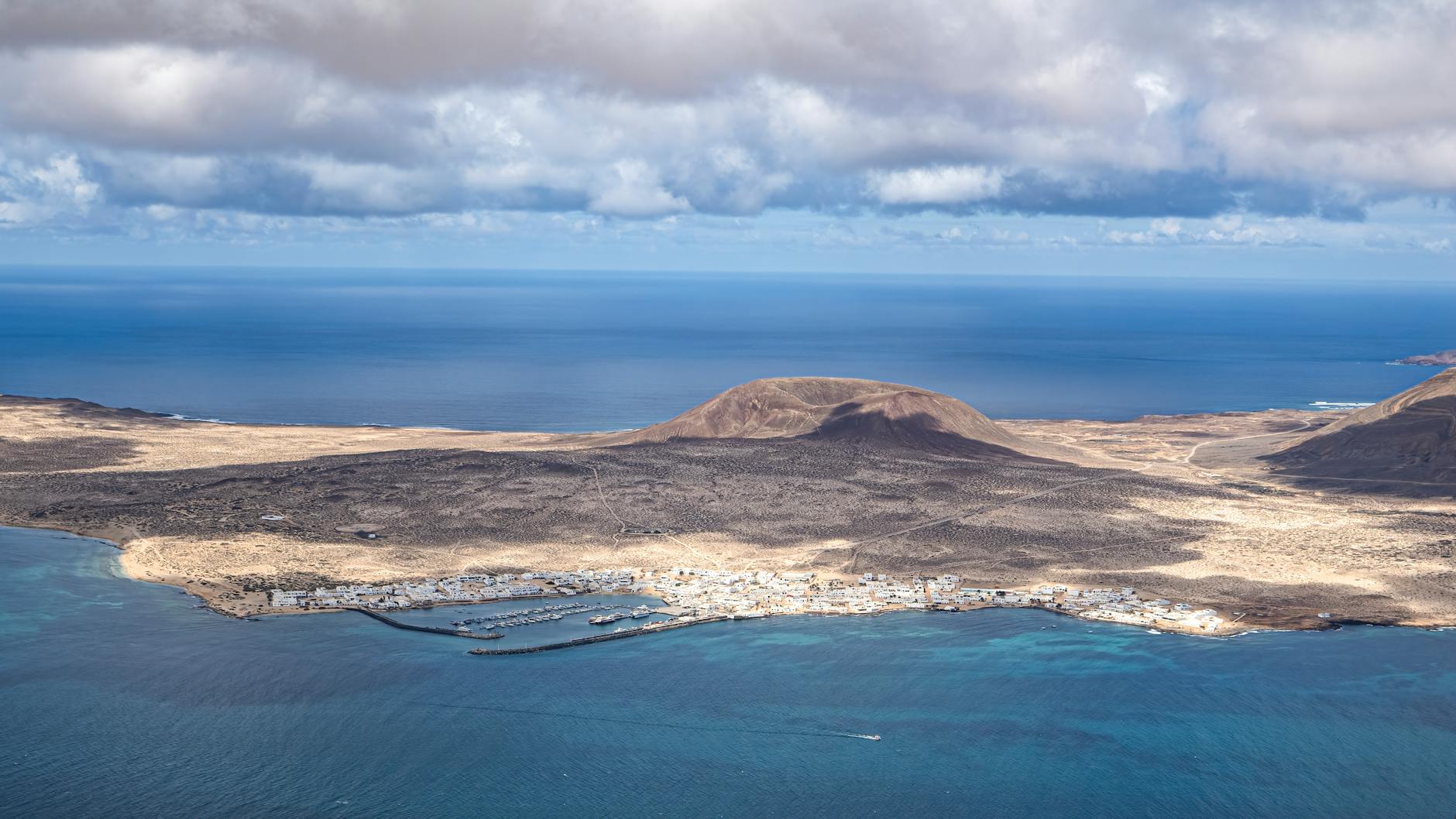 Drone shot of La Graciosa Island showing arid volcanic terrain and blue ocean