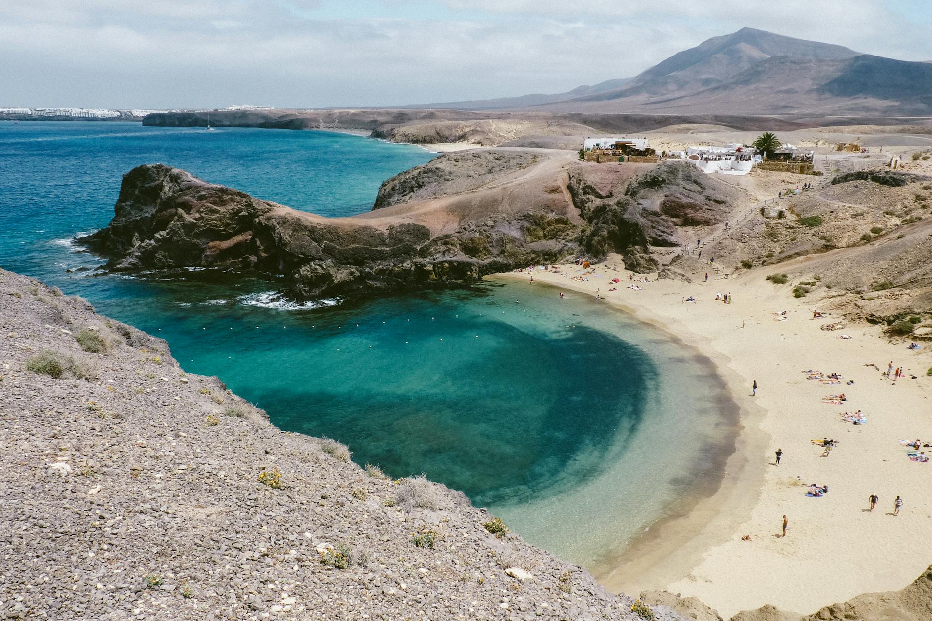 Sandy shore near turquoise ocean water and rocky coastline in Lanzarote