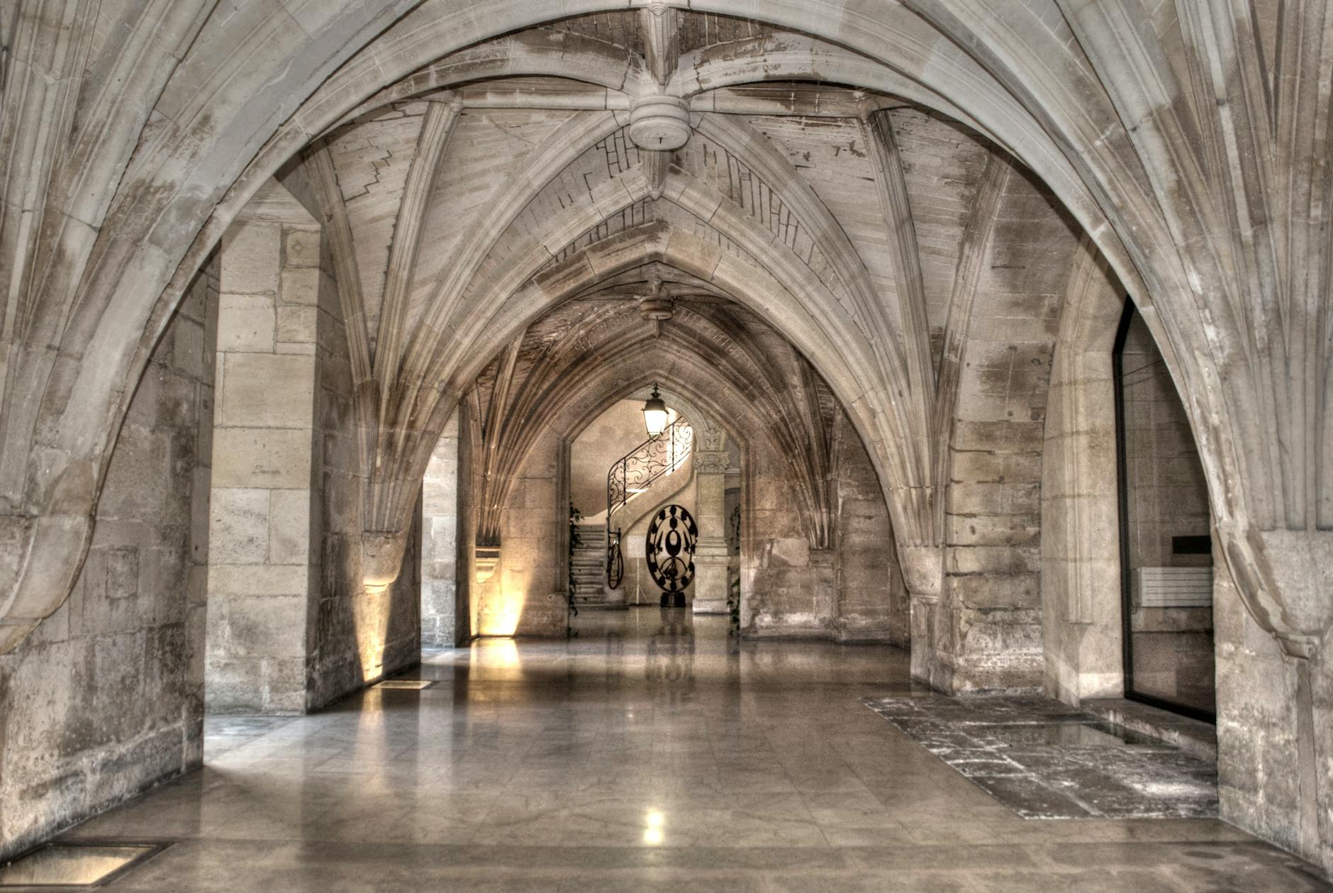Gothic corridor with vaulted stone ceilings and arched passageway