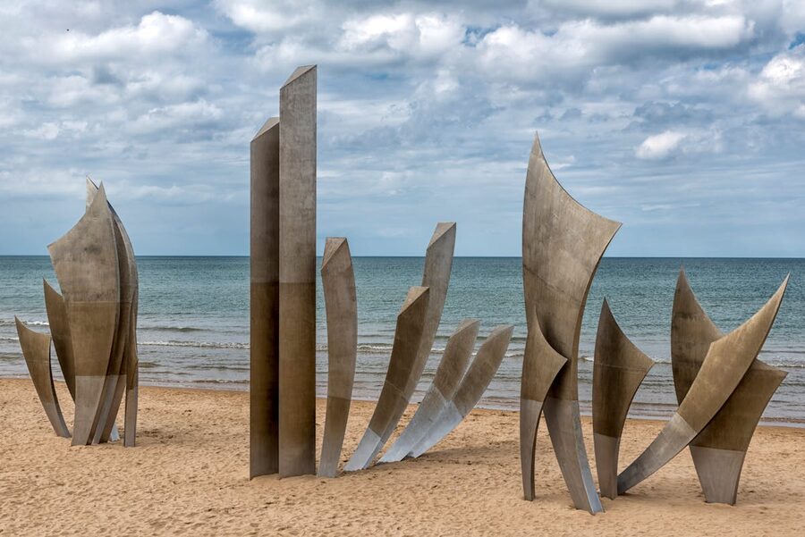 The Les Braves Memorial sculpture standing on the sands of Omaha Beach in Normandy