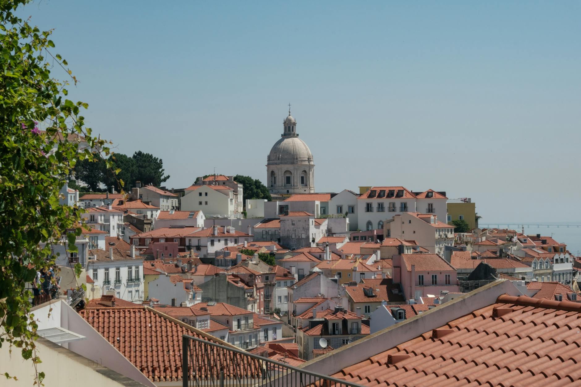 Red rooftops of Lisbon Alfama district with a church tower and river view
