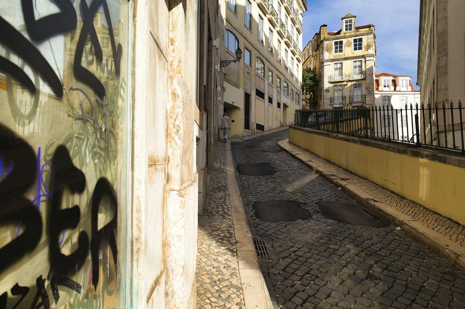 Narrow cobblestone street in Lisbon with colorful buildings and a vintage atmosphere
